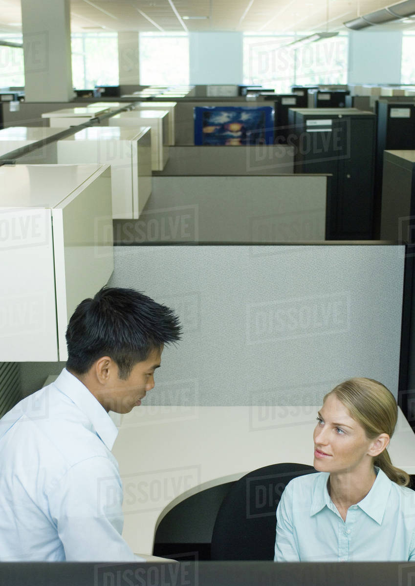 Two office workers talking in cubicle - Stock Photo - Dissolve