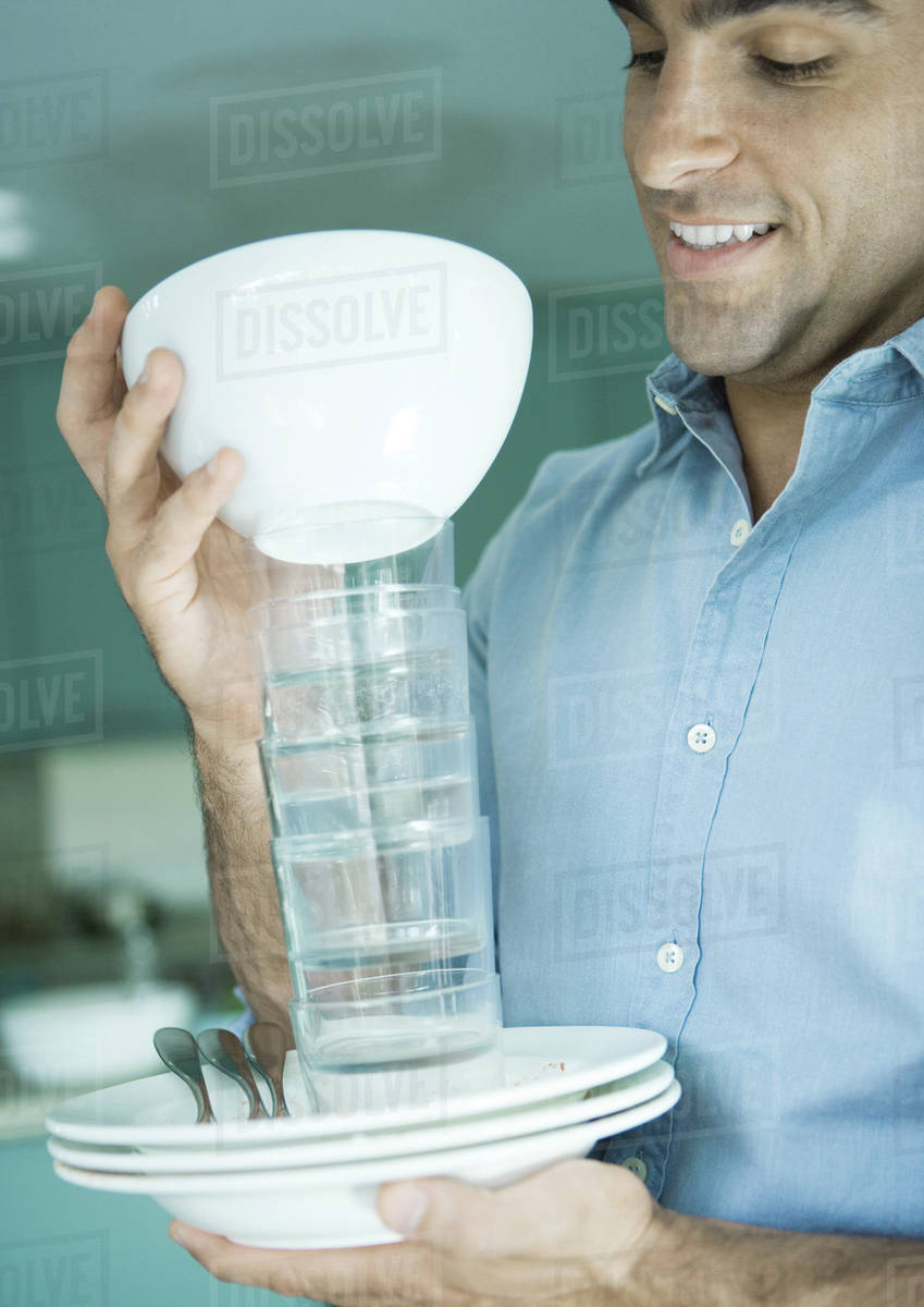 Man holding stack of dishes - Stock Photo - Dissolve