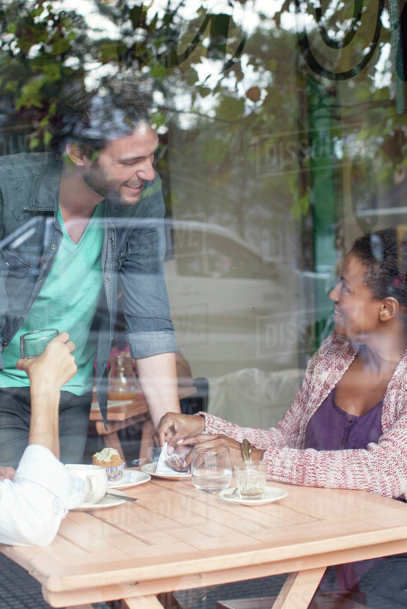 Waiter talking to customers in coffee shop - Stock Photo - Dissolve