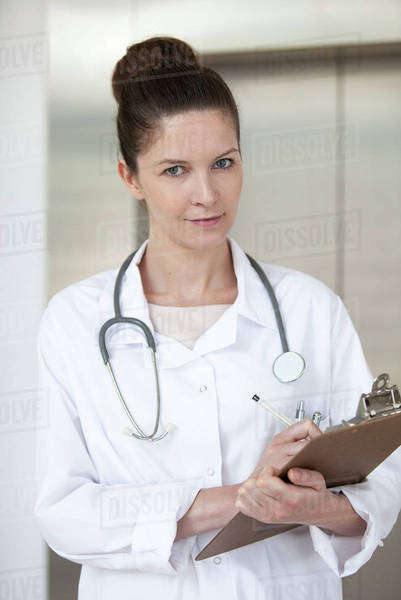 Doctor writing on medical chart, portrait - Stock Photo - Dissolve