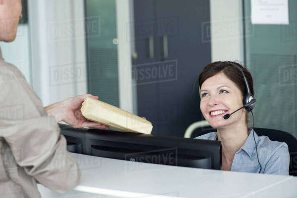 Receptionist receiving package from delivery person - Royalty-free ...