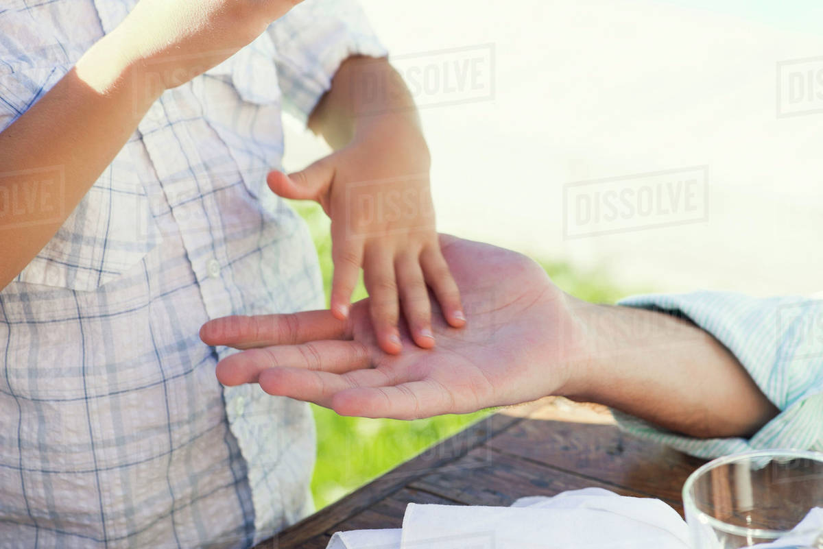 Child touching adult's hand, cropped - Stock Photo - Dissolve
