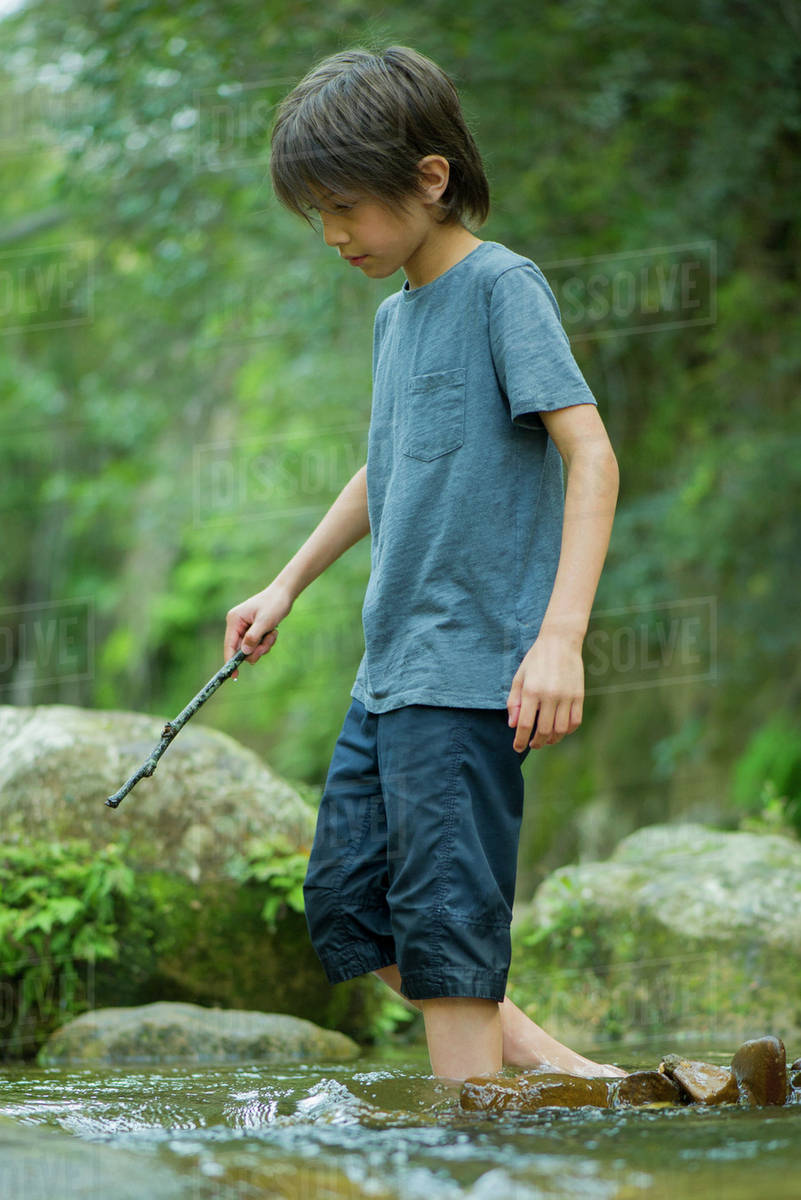 Boy wading in stream - Royalty-free Stock Photo | Dissolve