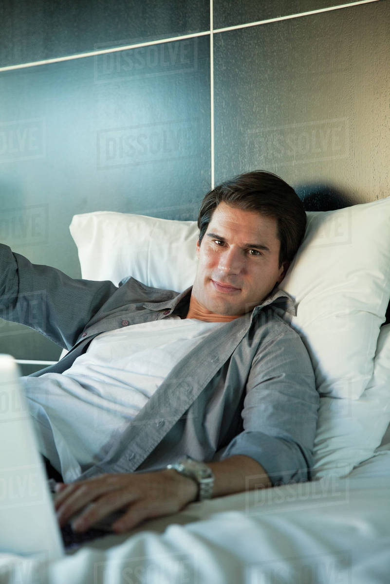 Man relaxing on bed, portrait - Royalty-free Stock Photo | Dissolve