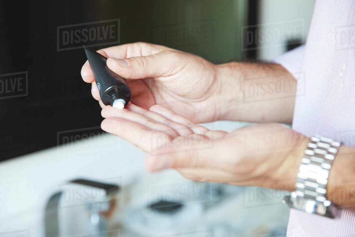 Man applying moisturizer to hands, cropped - Royalty-free Stock Photo | Dissolve
