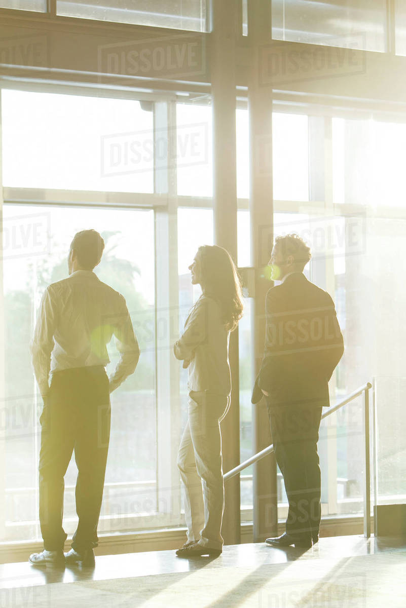 Business associates looking at view from office window - Royalty-free ...