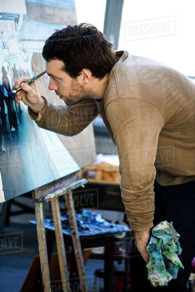 Artist working on oil painting in art studio - Stock Photo - Dissolve