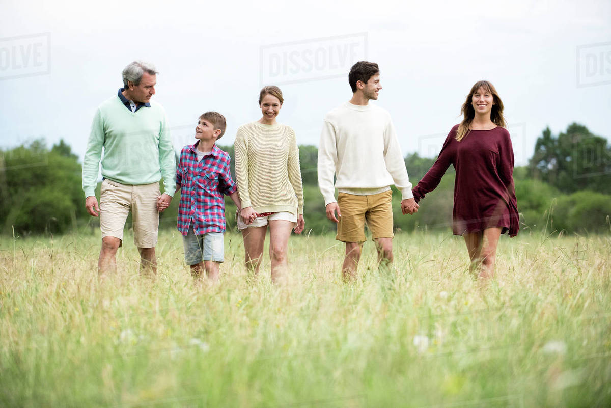 Family walking together in field - Royalty-free Stock Photo | Dissolve