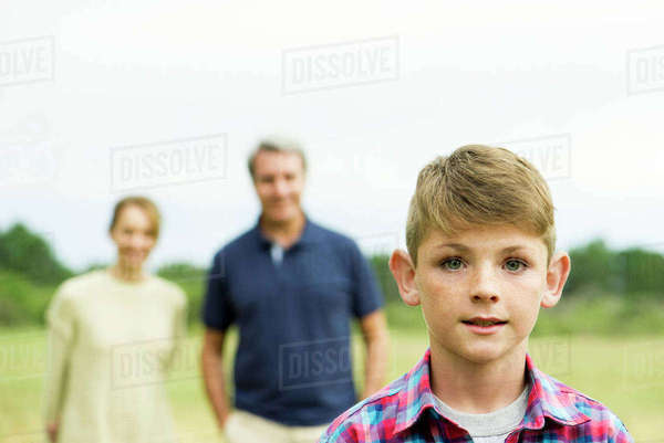 Boy with parents in background, portrait - Stock Photo - Dissolve