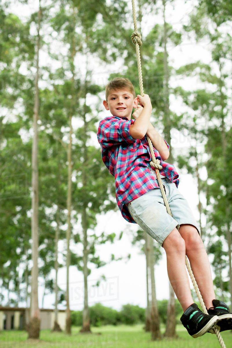 Boy swinging on rope outdoors - Stock Photo - Dissolve