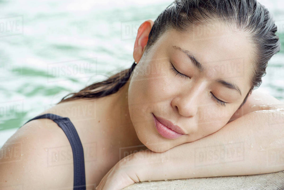 Woman at side of swimming pool resting head on arms - Stock Photo ...
