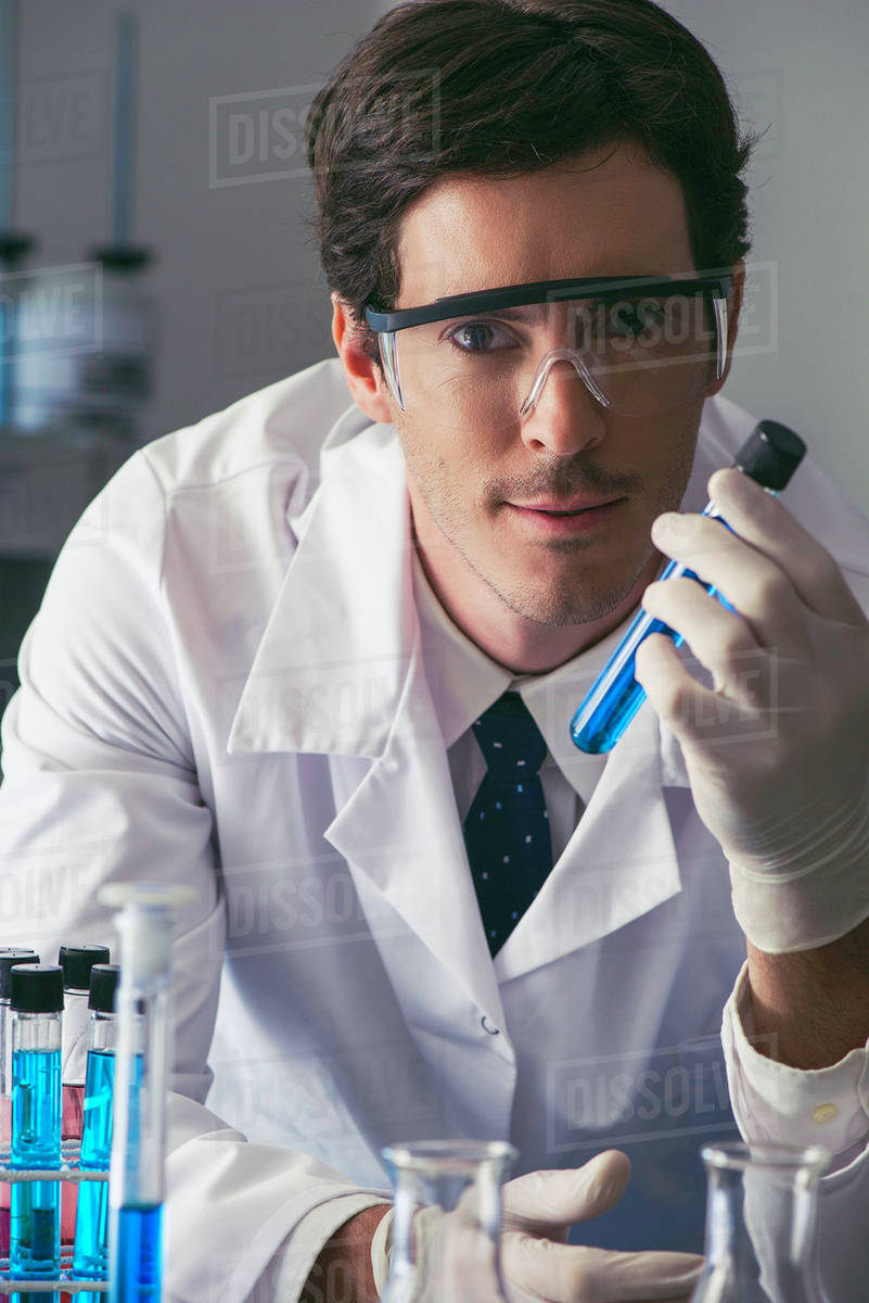 Scientist holding test tube in lab, looking at camera with determined ...