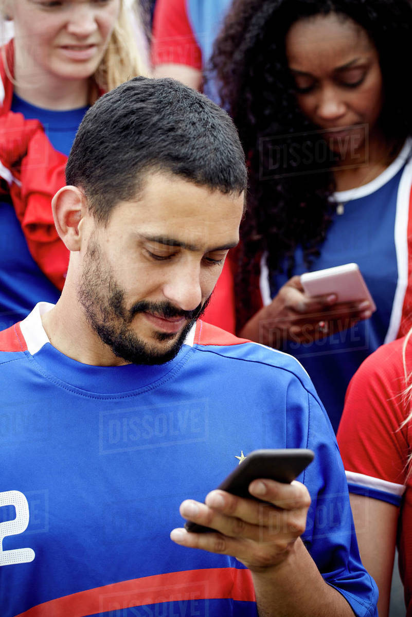 Man looking at smartphone during football match - Royalty-free Stock ...