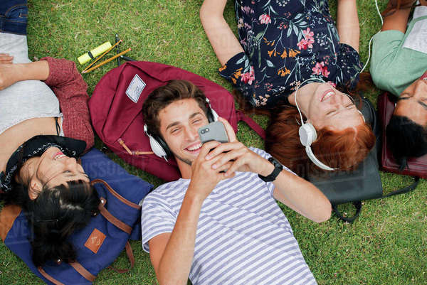 Group of college students relaxing together on grass between classes ...