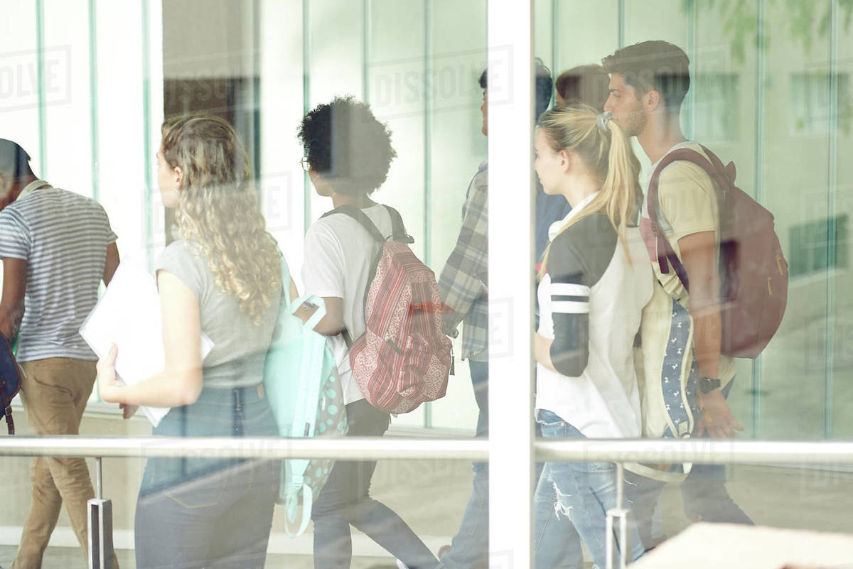 Students walking in school corridor, viewed through window - Stock ...