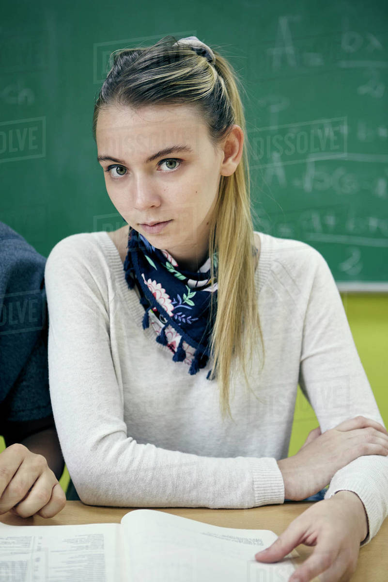 Young woman sitting in math class, portrait - Stock Photo - Dissolve