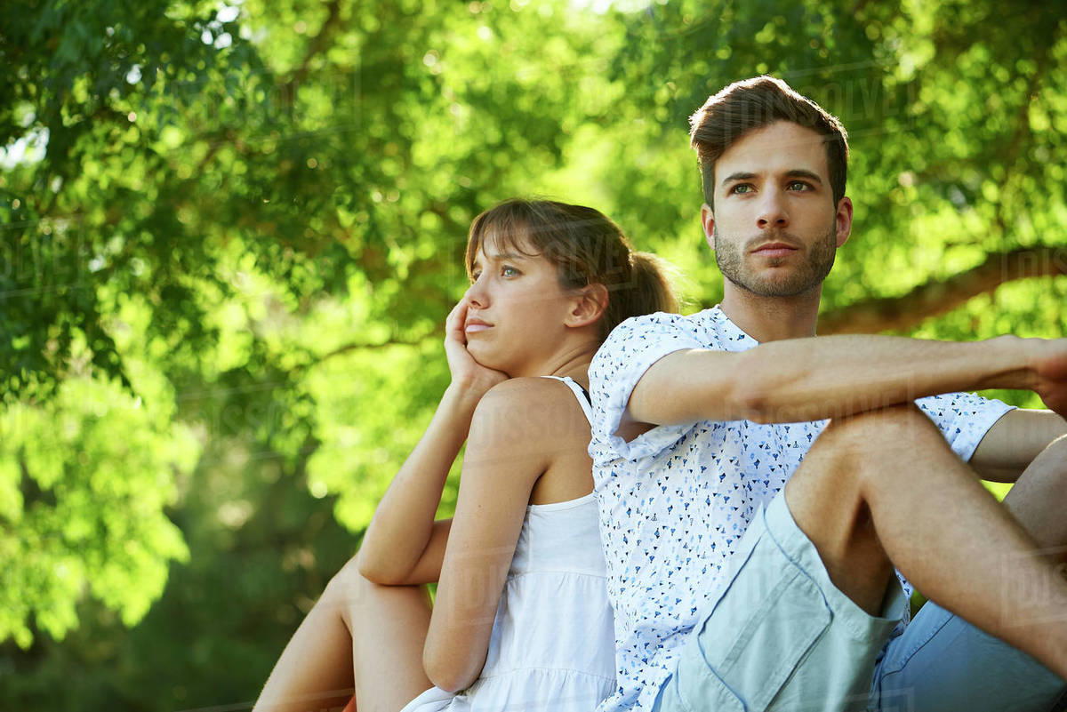 Angry young couple sitting in park - Stock Photo - Dissolve
