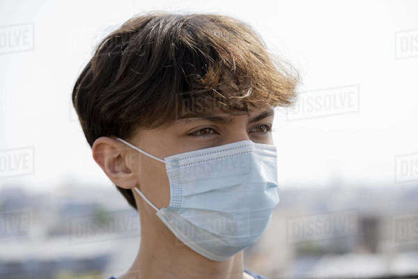 Close up of teenage boy wearing blue surgical mask outdoors - Royalty ...