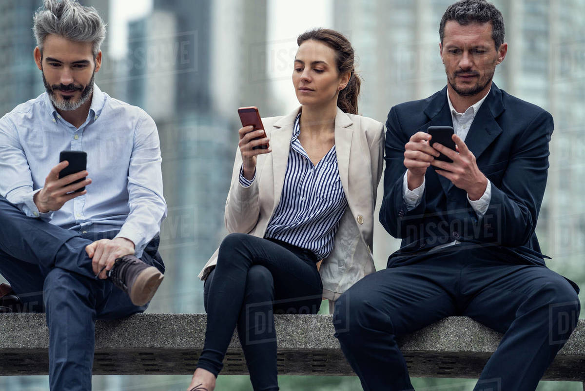 Business people using smartphones in public park - Stock Photo - Dissolve