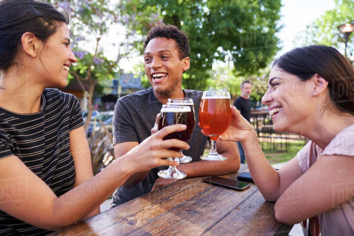 Group of happy friends raising their beers glasses in celebration at ...