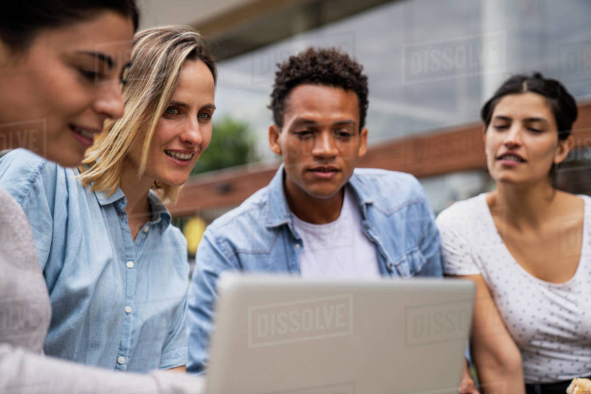 Diverse group of freelance contractor looking at a laptop's screen in ...