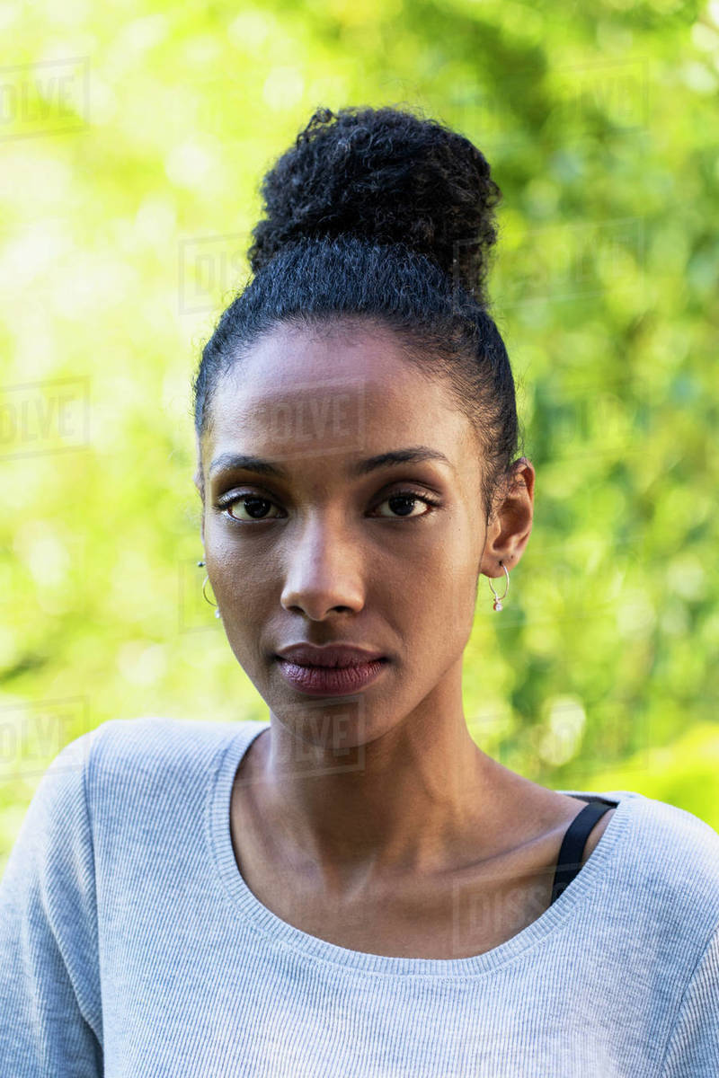 Front view portrait of young adult woman looking at the camera standing ...