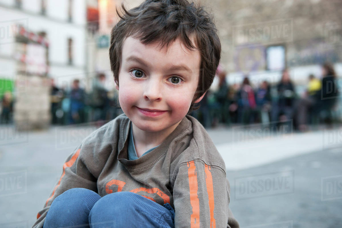 Boy sitting outdoors in urban setting, portrait - Royalty-free Stock ...