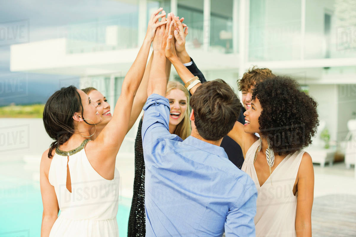 Friends high fiving at poolside - Royalty-free Stock Photo | Dissolve