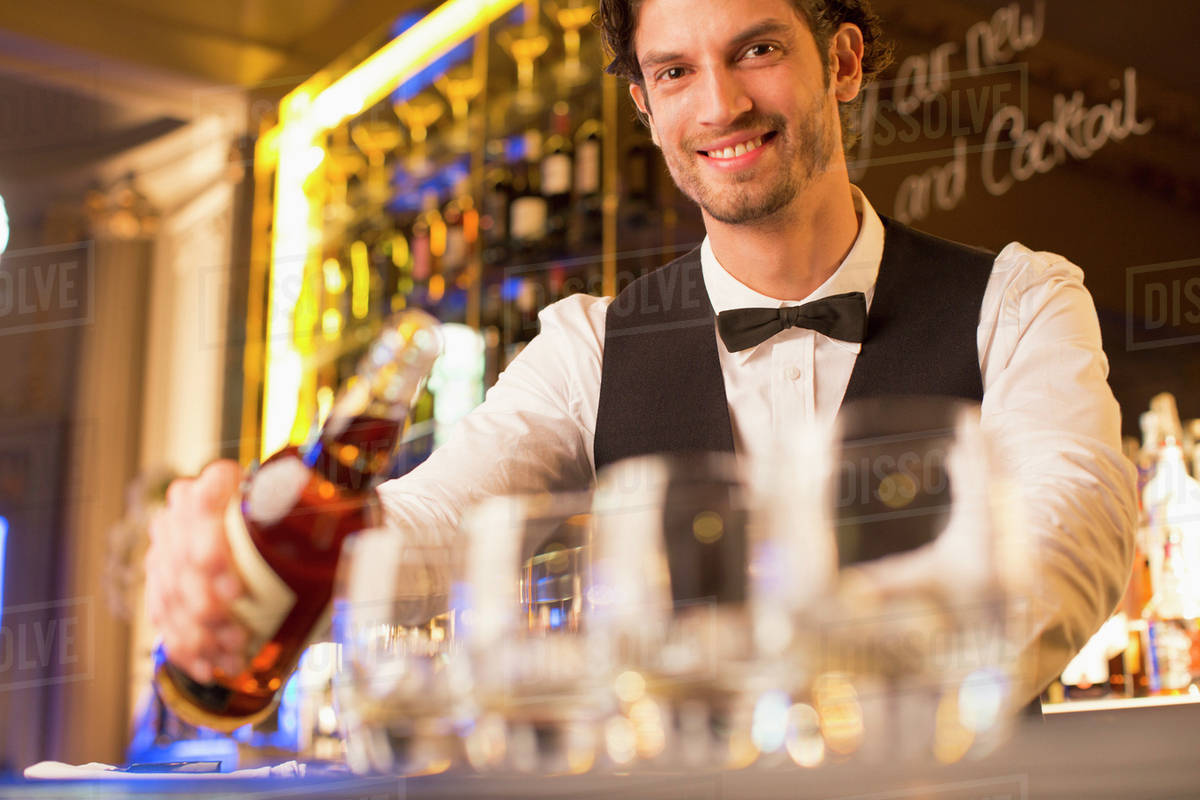 Portrait of well dressed bartender pouring bourbon in luxury bar ...