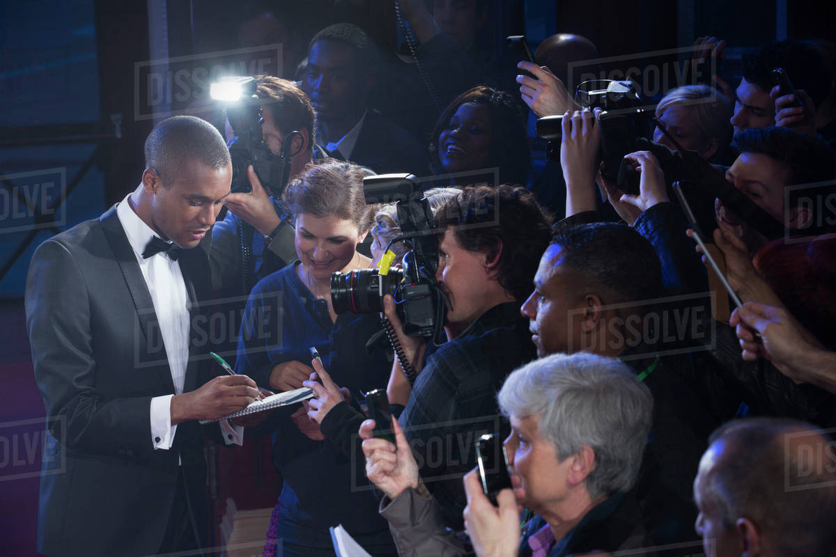 Well dressed male celebrity signing autographs at red carpet event ...