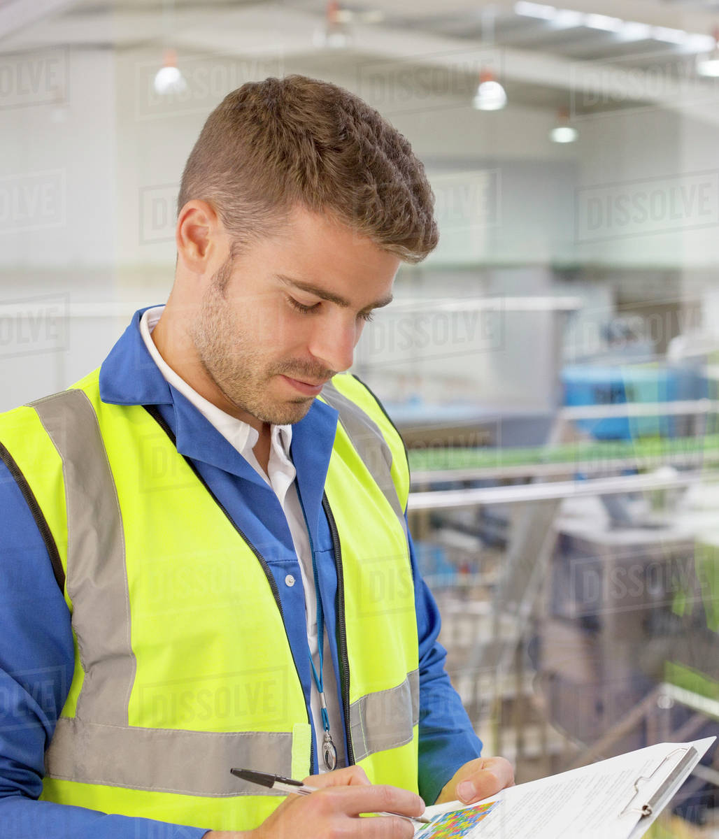 Worker with clipboard in factory - Royalty-free Stock Photo | Dissolve