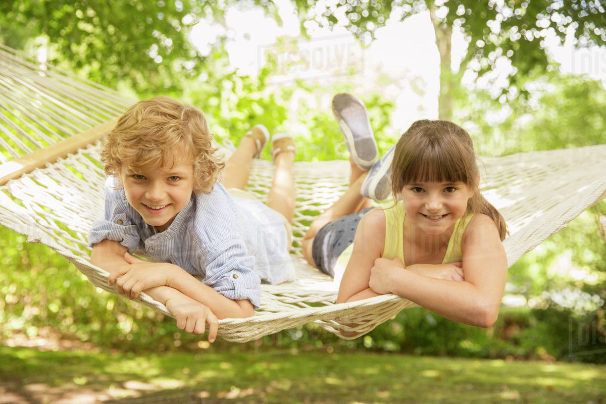 Children relaxing together in hammock - Stock Photo - Dissolve