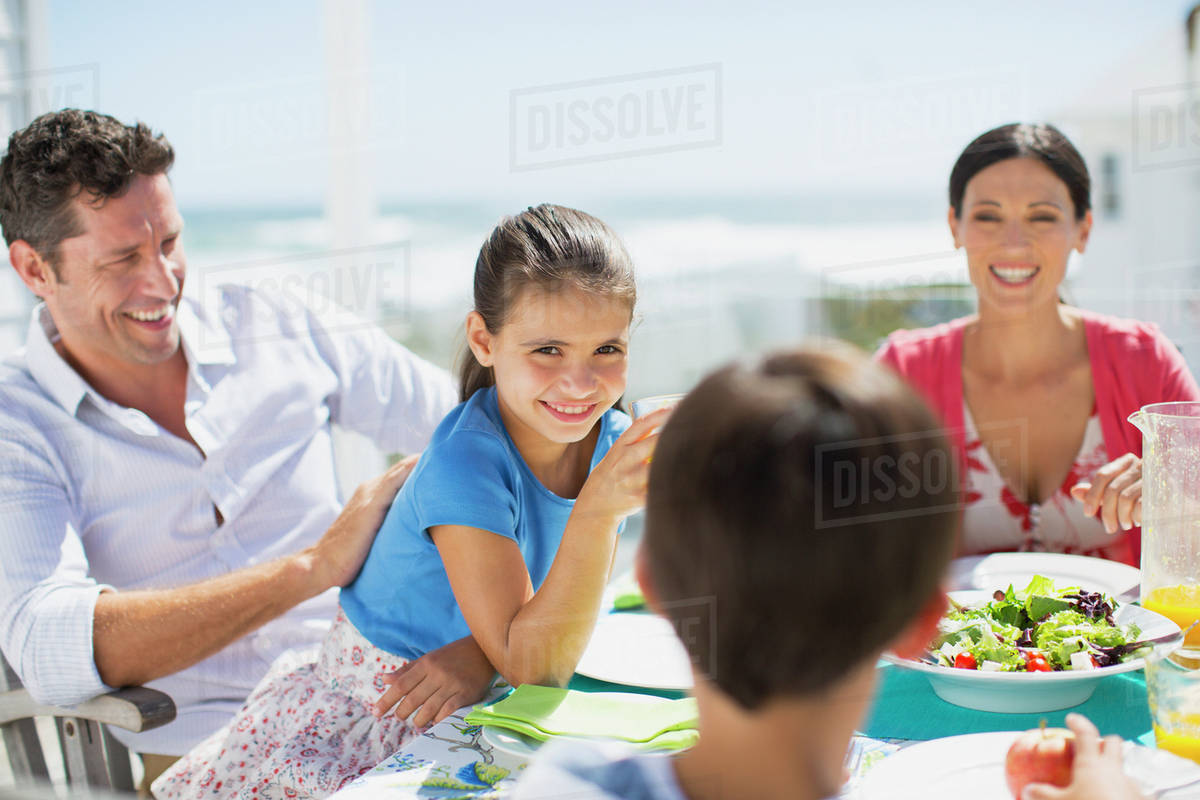 Family eating lunch at table on sunny patio - Royalty-free Stock Photo ...