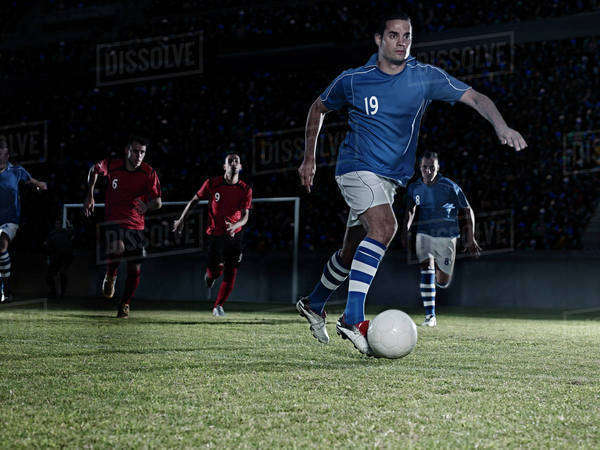 Soccer players chasing ball on field - Stock Photo - Dissolve
