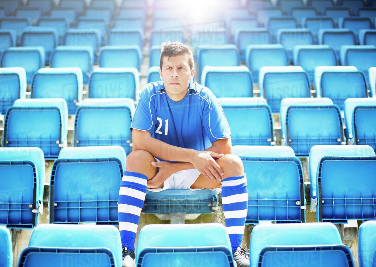 Soccer player sitting in empty stadium - Stock Photo - Dissolve