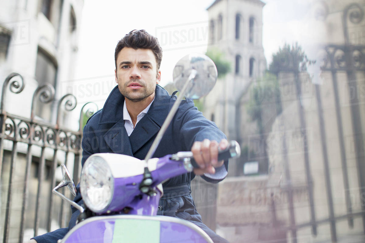 Man driving scooter on city street - Royalty-free Stock Photo | Dissolve