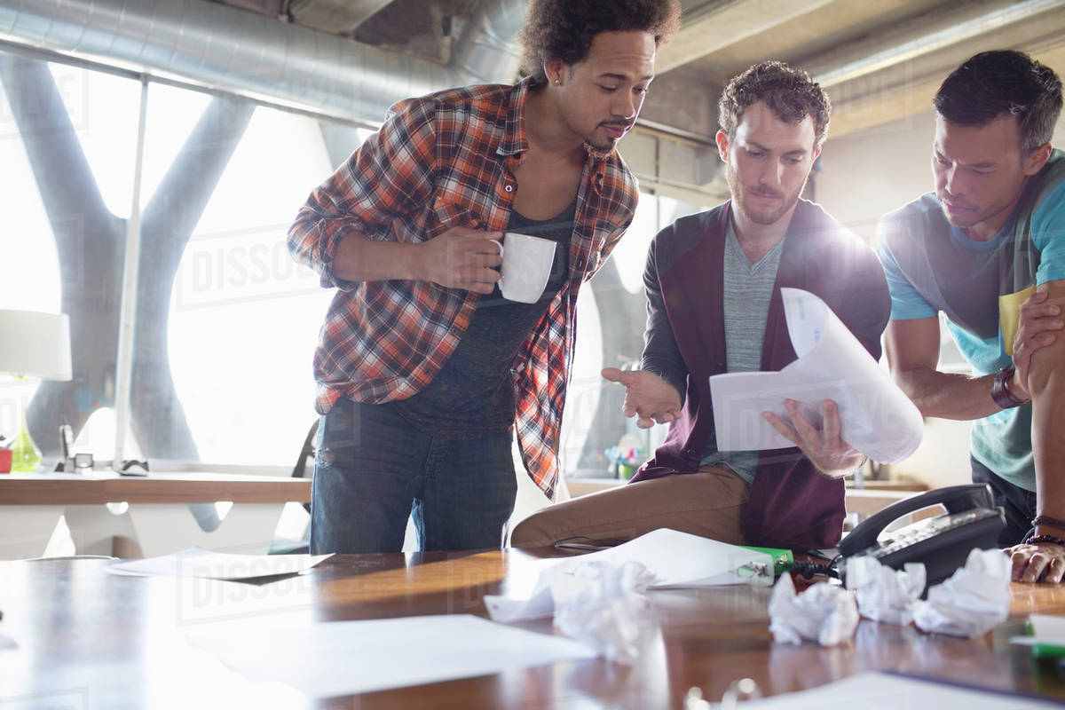 Creative businessmen reviewing paperwork in meeting - Royalty-free ...