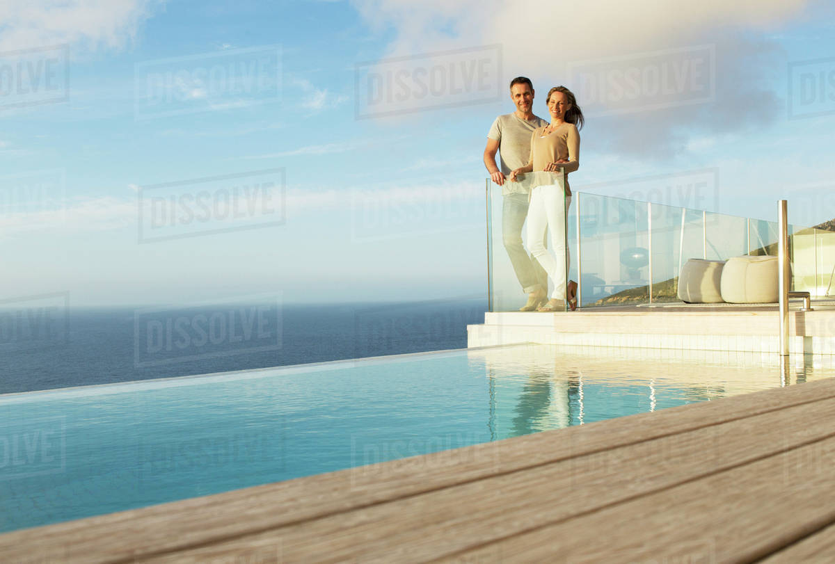 Couple on modern balcony overlooking ocean - Stock Photo - Dissolve