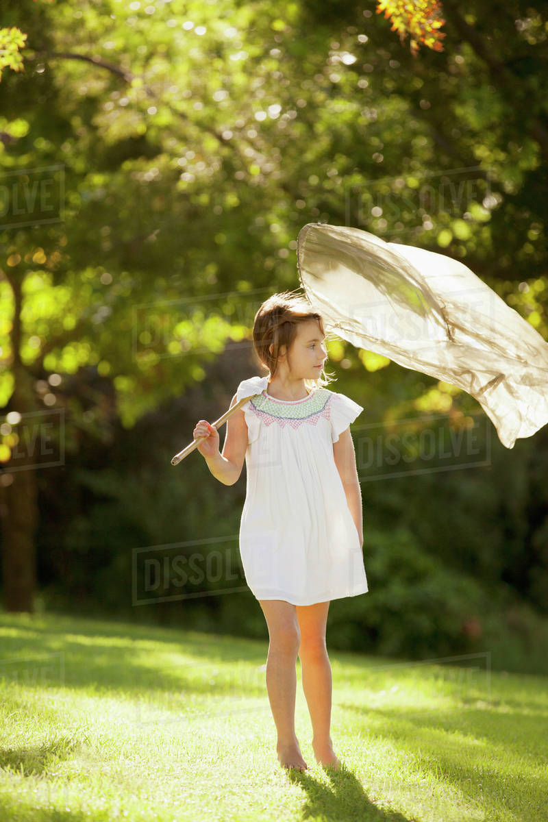 Girl carrying butterfly net in grass - Royalty-free Stock Photo | Dissolve