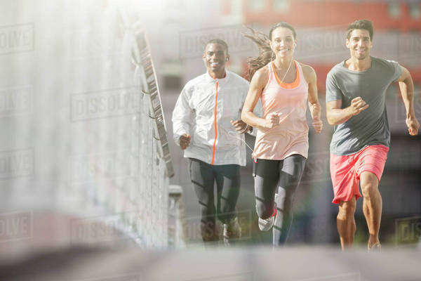 Friends running through city streets together - Stock Photo - Dissolve