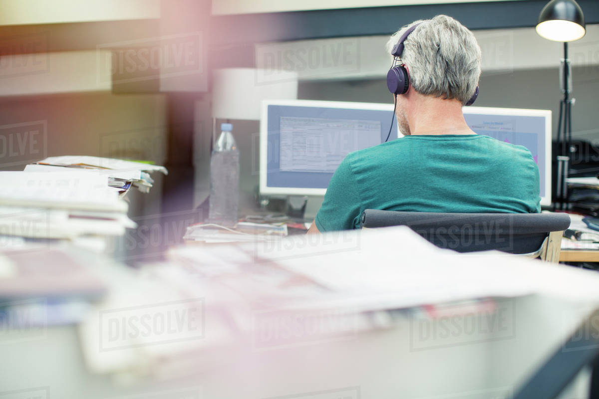 Businessman listening to headphones in office - Royalty-free Stock ...