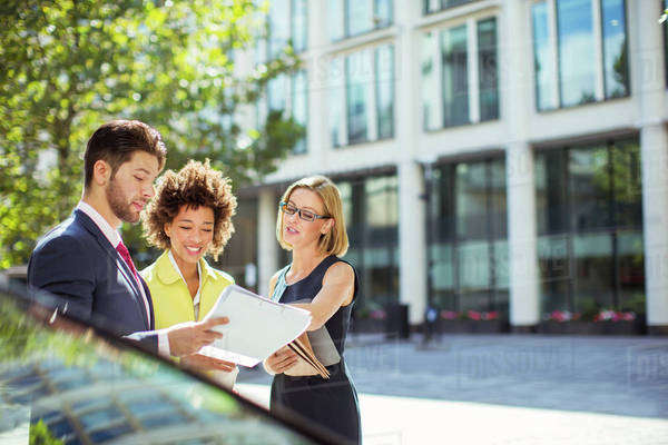 Business people reading paperwork in city - Stock Photo - Dissolve