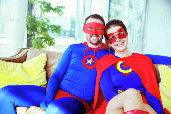 Superhero couple smiling on living room sofa - Stock Photo - Dissolve