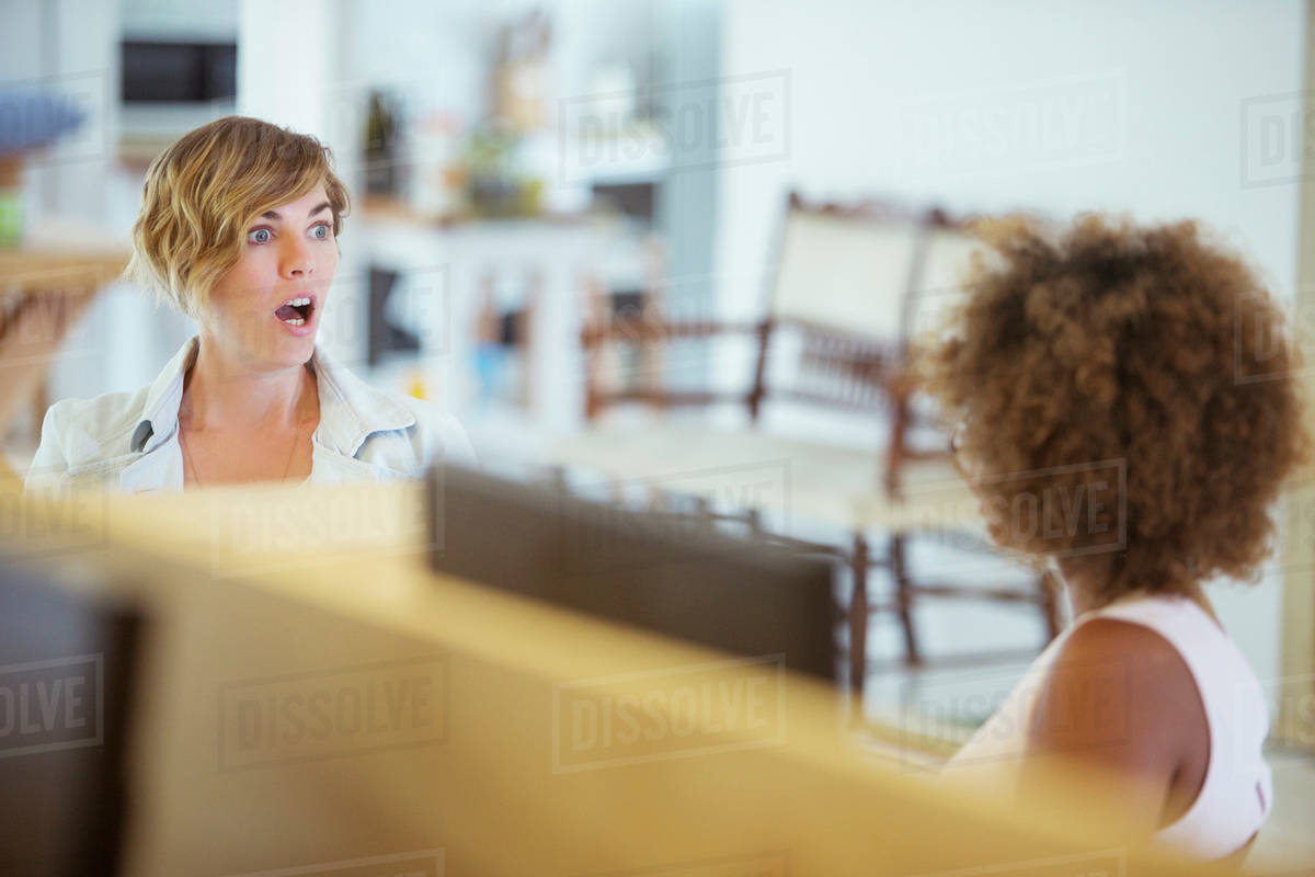 Female colleagues talking in office, feeling surprised - Stock Photo ...