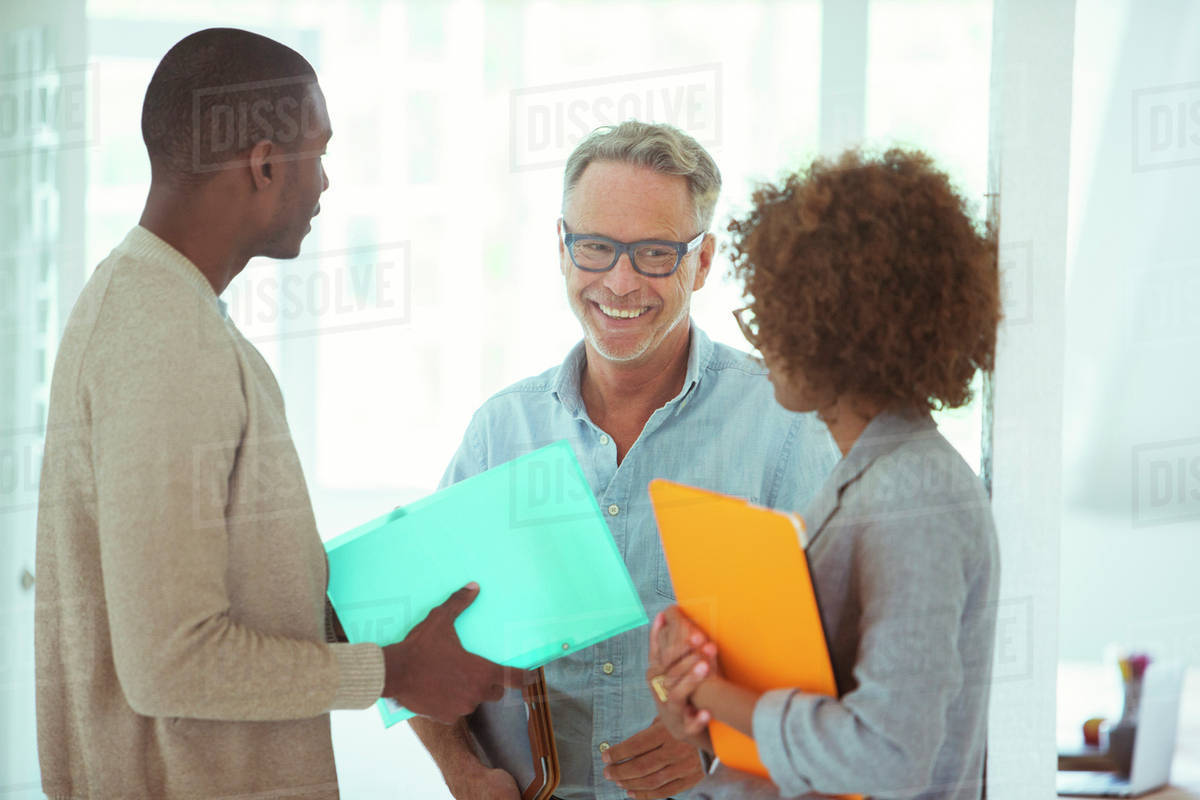 Three office workers talking at office - Stock Photo - Dissolve