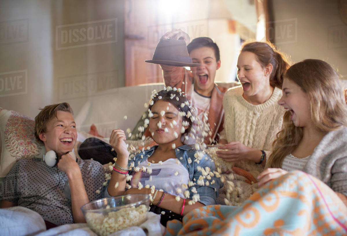 Group of teenagers throwing popcorn on themselves while sitting on sofa ...