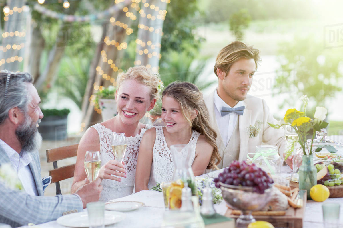 Young couple and their guests sitting at table during wedding reception ...