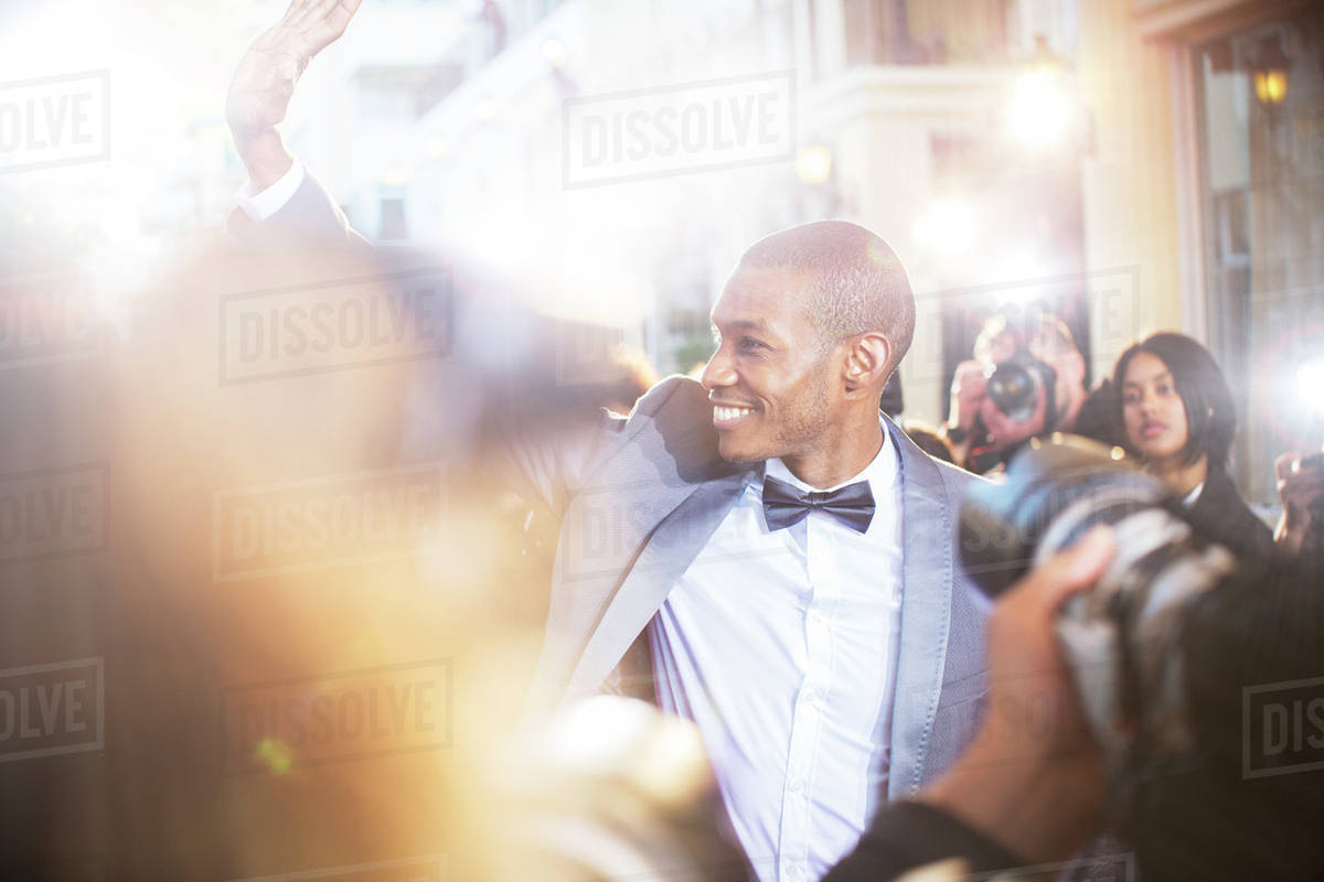 Smiling celebrity waving to paparazzi photographers at event - Stock ...