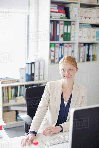 Portrait of smiling businesswoman at desk in office - Royalty-free ...