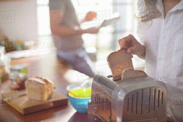 Woman putting bread in toaster - Royalty-free Stock Photo | Dissolve